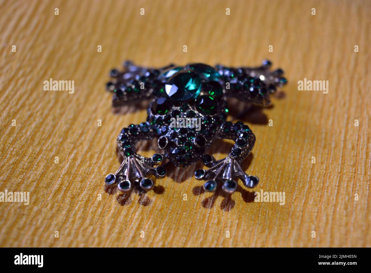 A beautiful female jewelry, a jewel with green stones, a metal frog, a ...