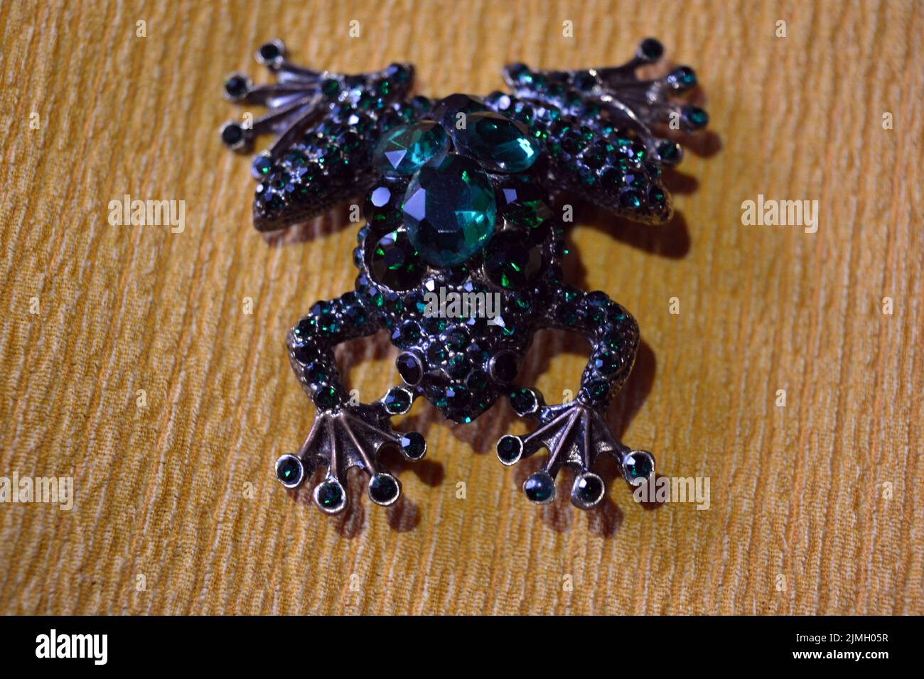 A beautiful female jewelry, a jewel with green stones, a metal frog, a ...