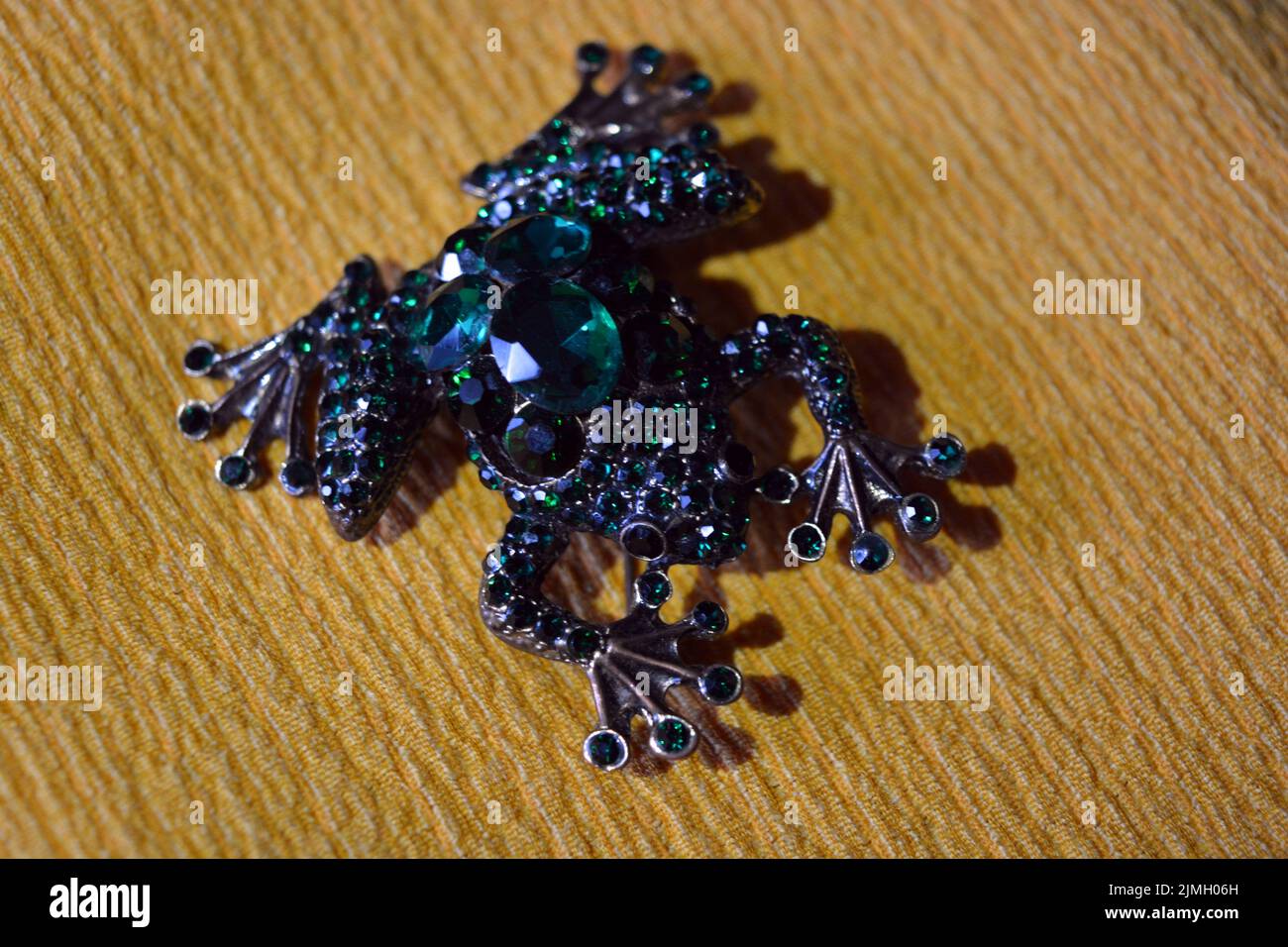 A beautiful female jewelry, a jewel with green stones, a metal frog, a ...