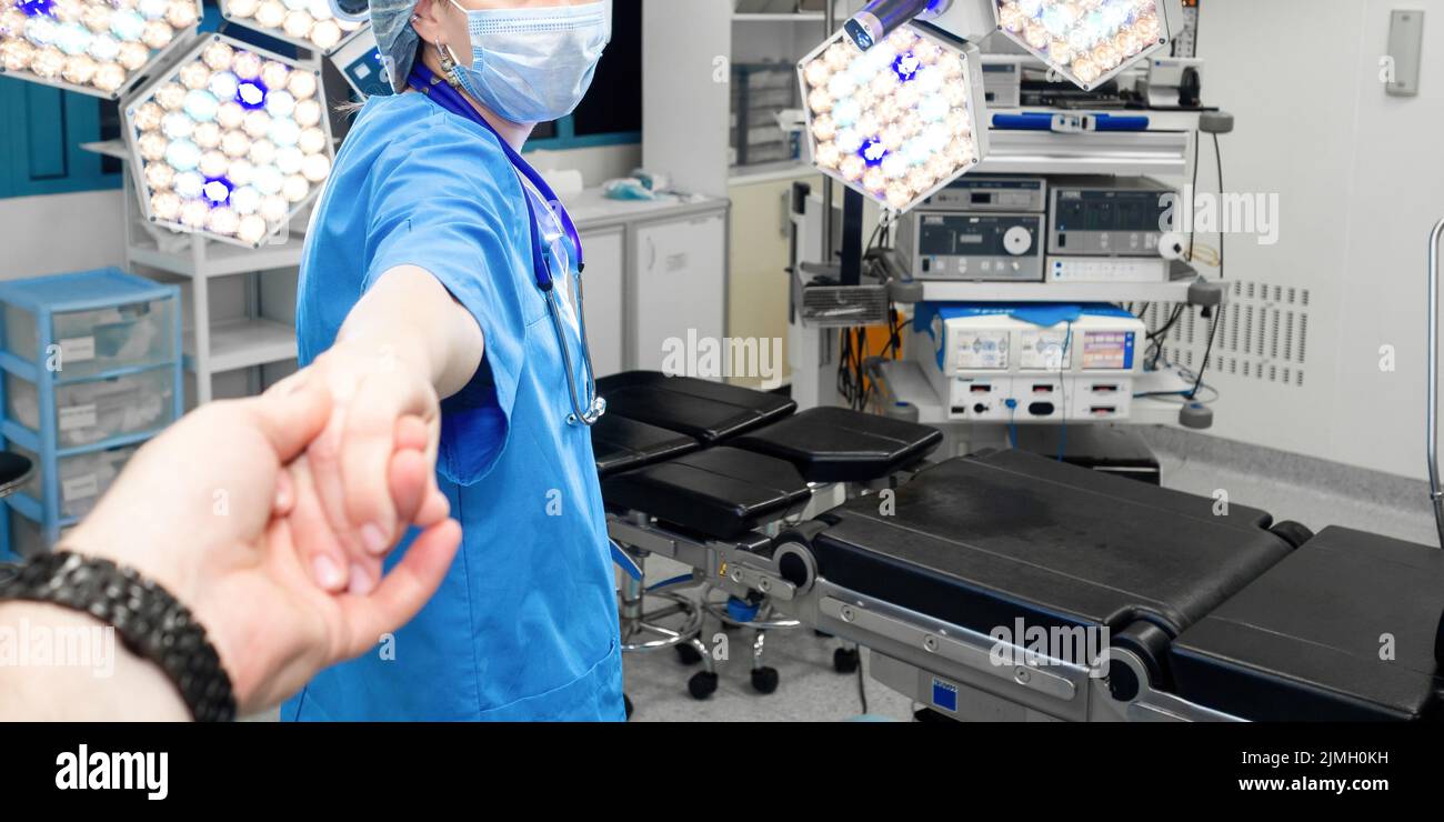 A female doctor pulls a human by the hand into the operating room Stock ...