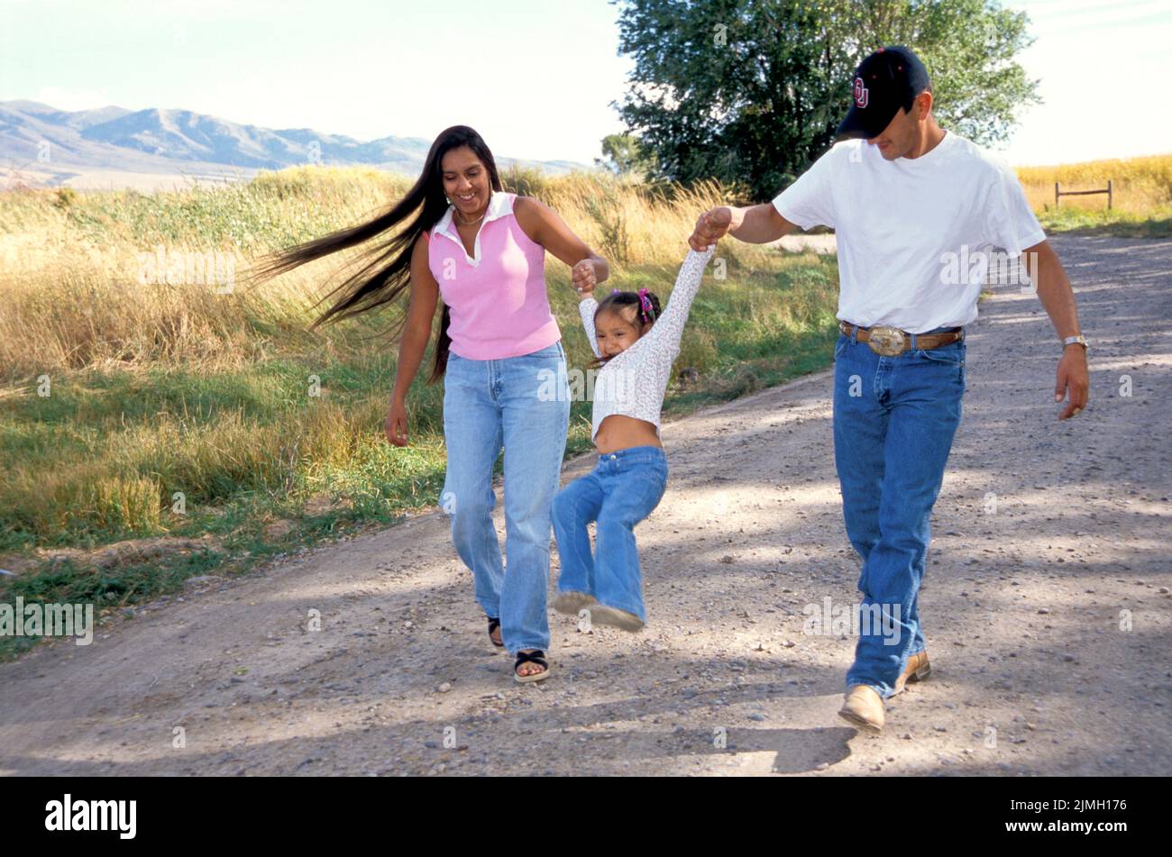 Native American parents walk down a country road with young daughter ...