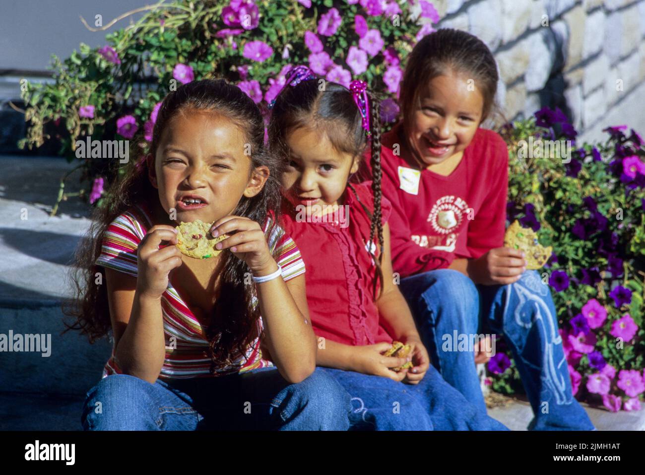 Three Native American children take time to eat a snack during play ...