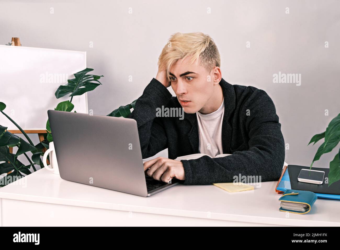 A young, frustrated, shocked man holds on to his head staring at a ...