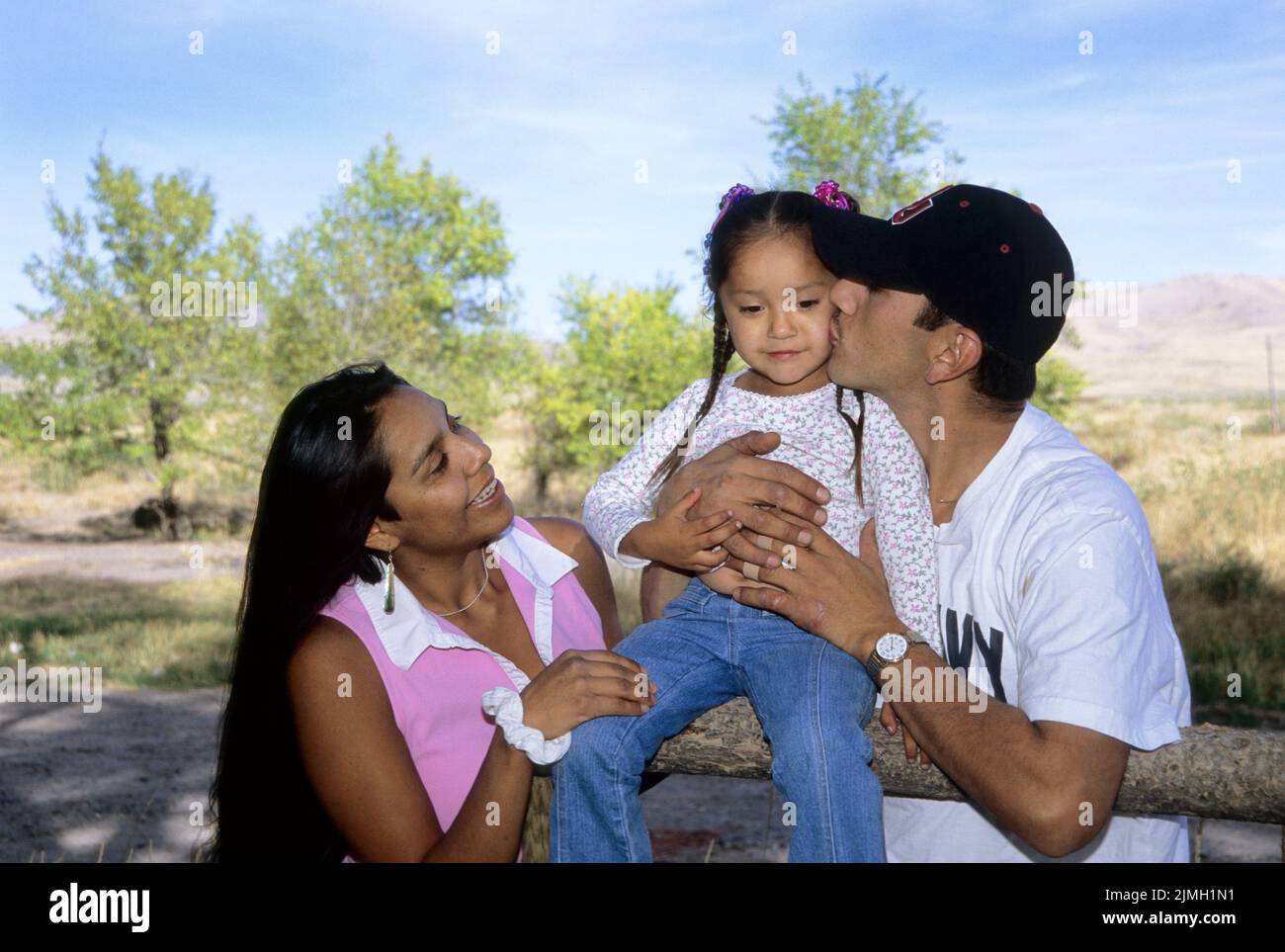 Native American family of 4 year old daughter with parents sit on a fen ...