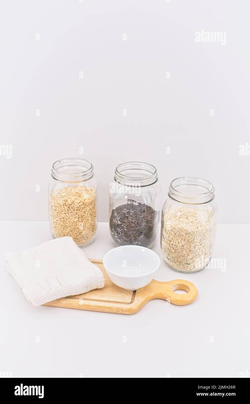 glass jar and containers with organic farming rice on a white table and ...