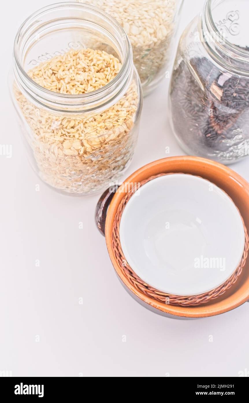glass jar and containers with organic farming rice on a white table and ...