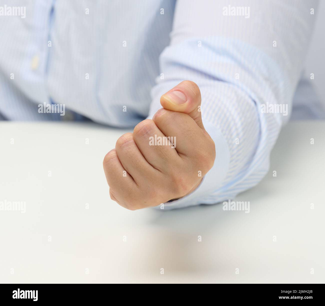Female hand folded into a fist on a white table. Strict leader ...