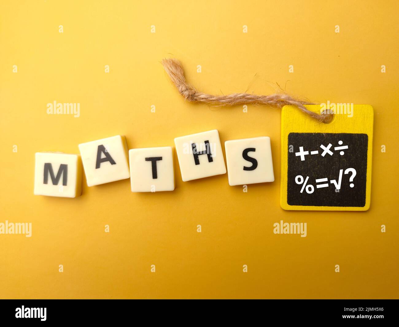 Toy cubes with the word MATHS and math symbols on blackboard on yellow ...