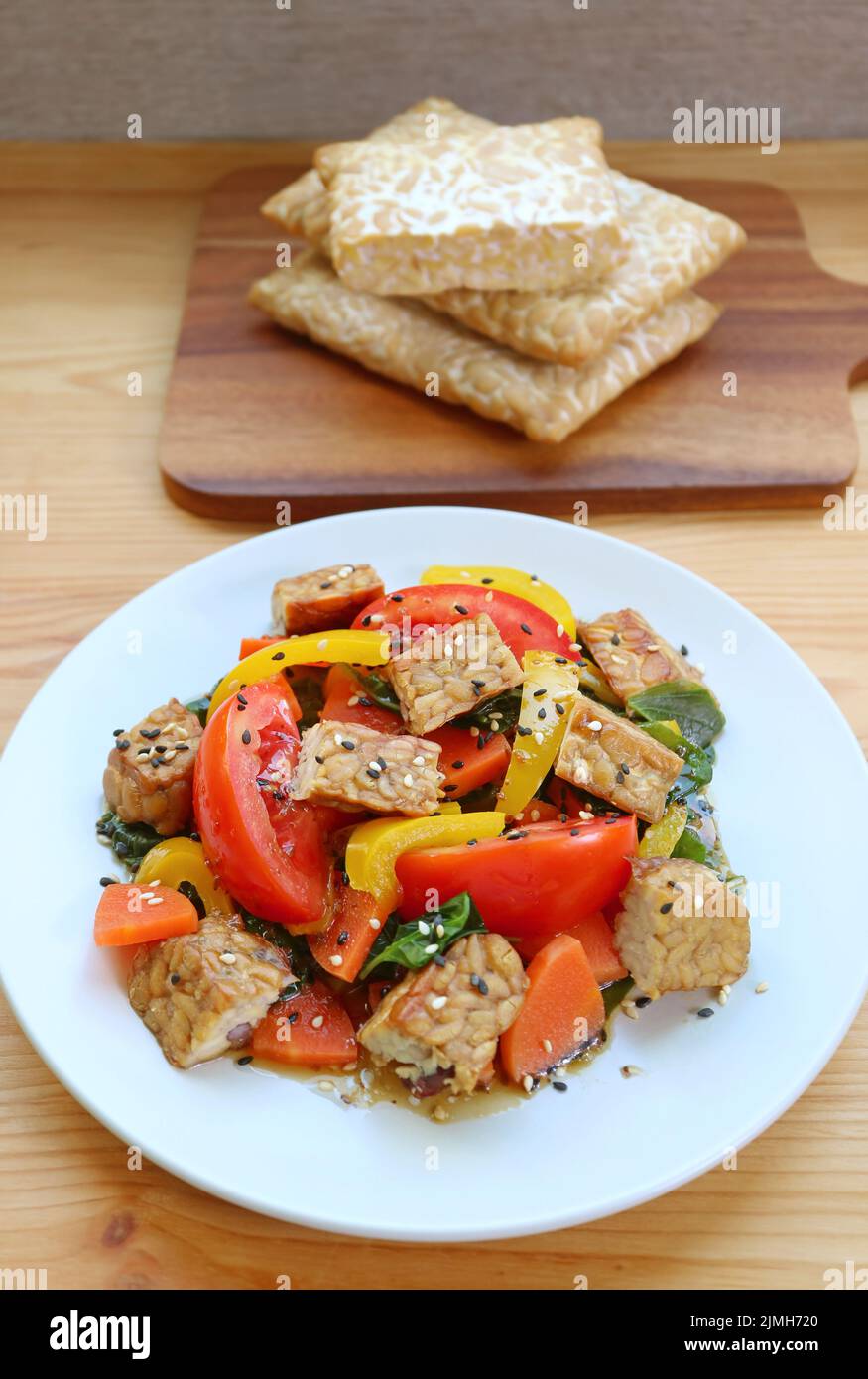 Mouthwatering vegetables salad and roasted Tempeh cubes with stack of ...