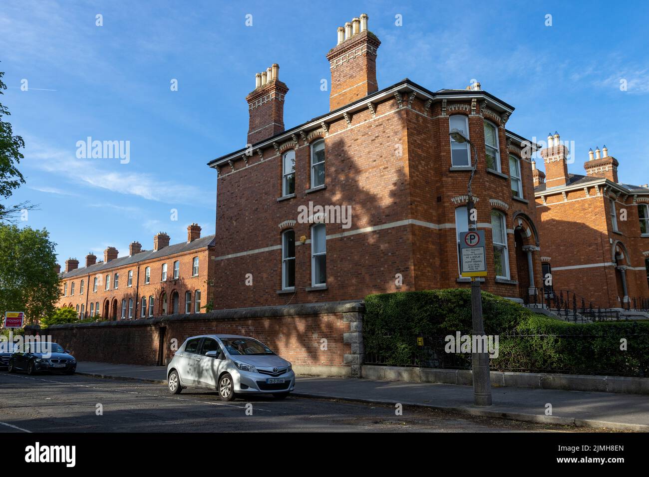 A pretty brick building in Dublin Ireland with parked cars on a sunny ...