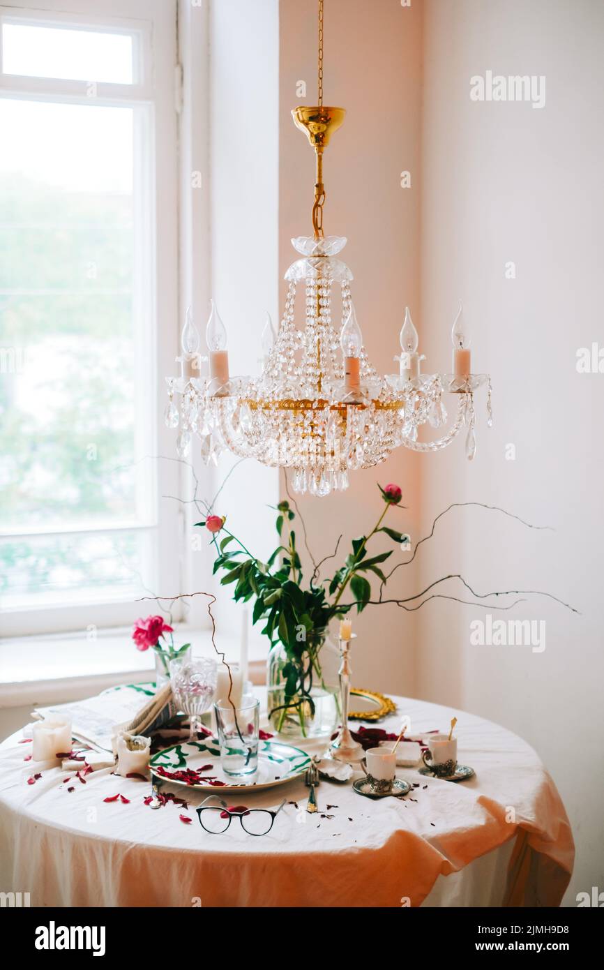 Interior of bright living room with chandelier and table with flowers ...