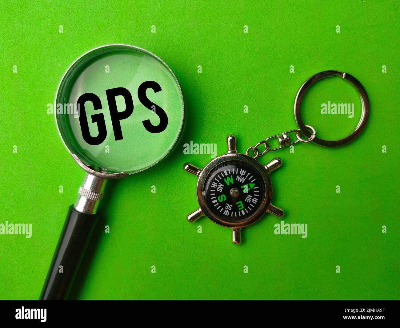A top view of a compass and magnifying glass with the word GPS on green ...