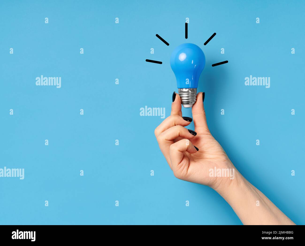 Female hand hold light bulb on blue background with copy space for text ...