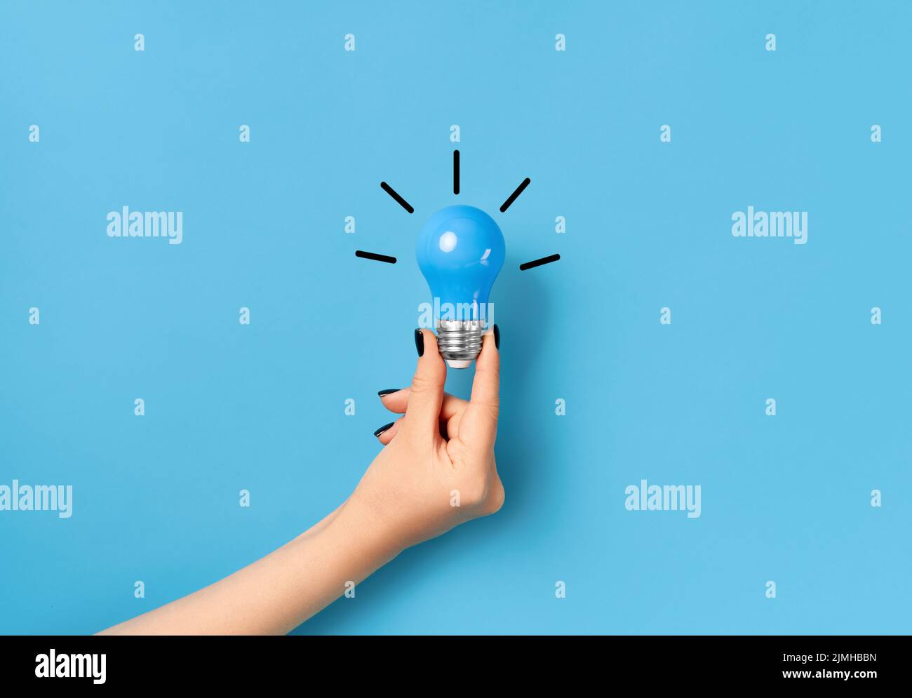 Female hand hold light bulb on blue background with copy space for text ...