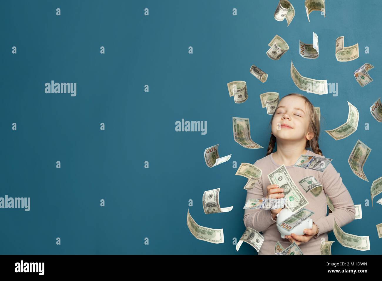 Beautiful happy kid in the rain of money on blue background with copy ...