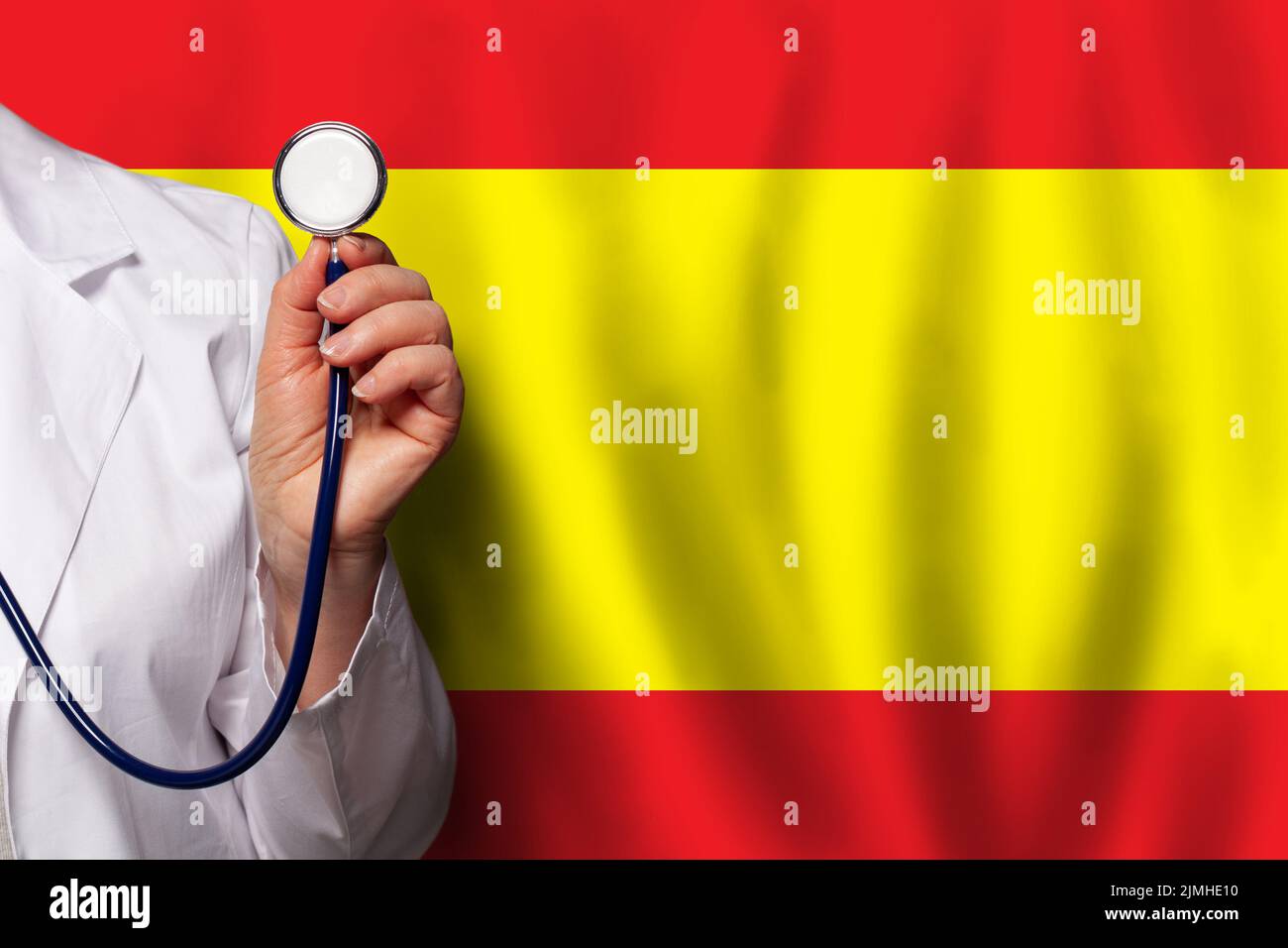 Spanish medical worker's hand with stethoscope on flag of Spain ...