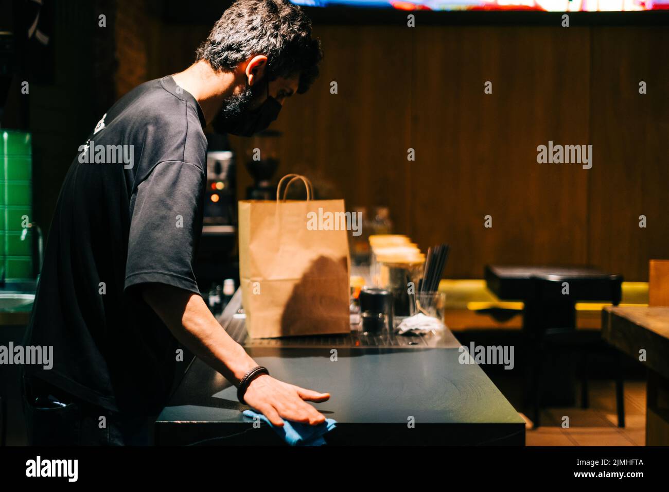 Young caucasian man asian bistro worker cleaning table on the bar ...