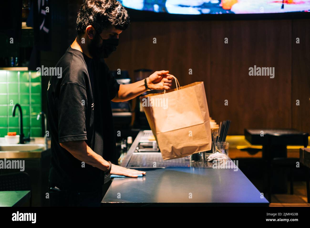 Young caucasian man asian bistro worker cleaning table on the bar ...