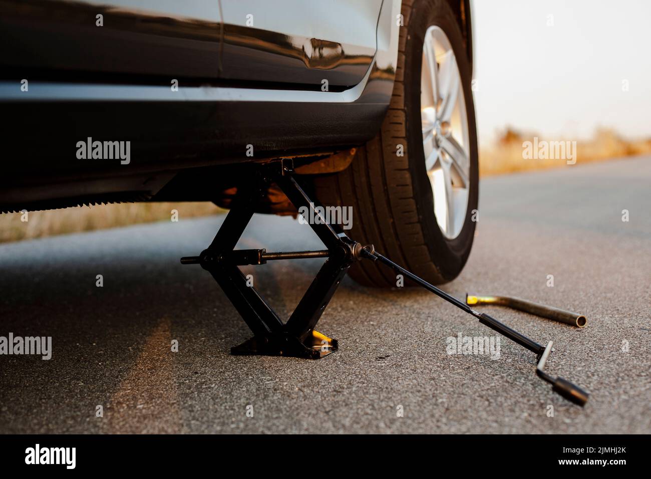 Black car lifted up by jack screw Stock Photo - Alamy