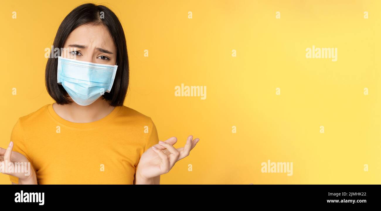 Close up portrait of confused asian woman in medical face mask ...