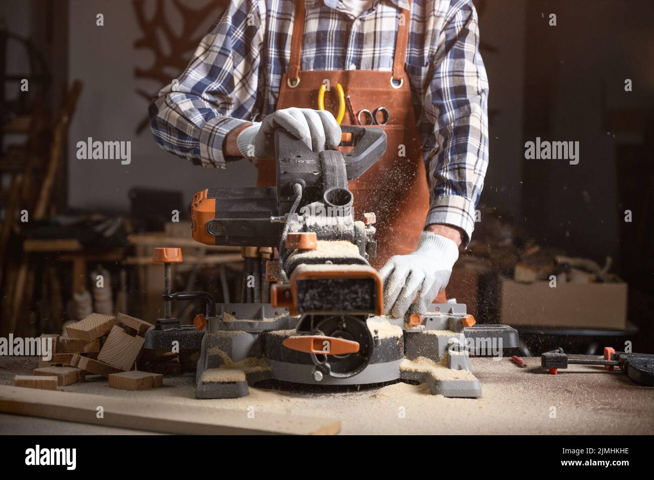 Carpenter is sawing a wood plank with electric circular saw machine in ...
