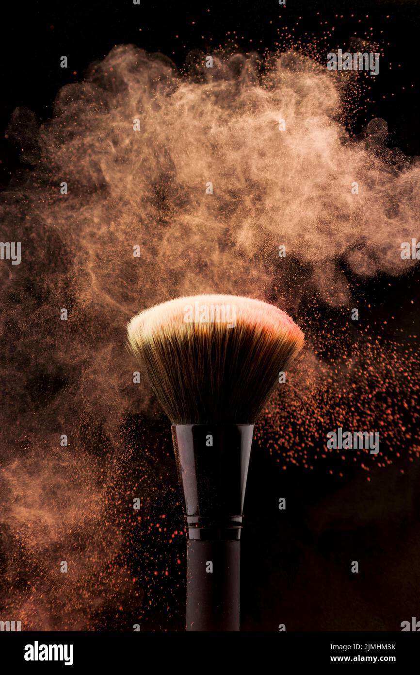 Makeup brush with peach color powder splash Stock Photo - Alamy