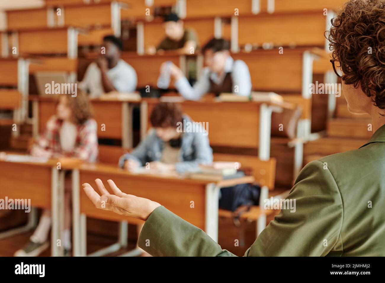 Young confident college teacher or lecturer explaining one of lesson ...