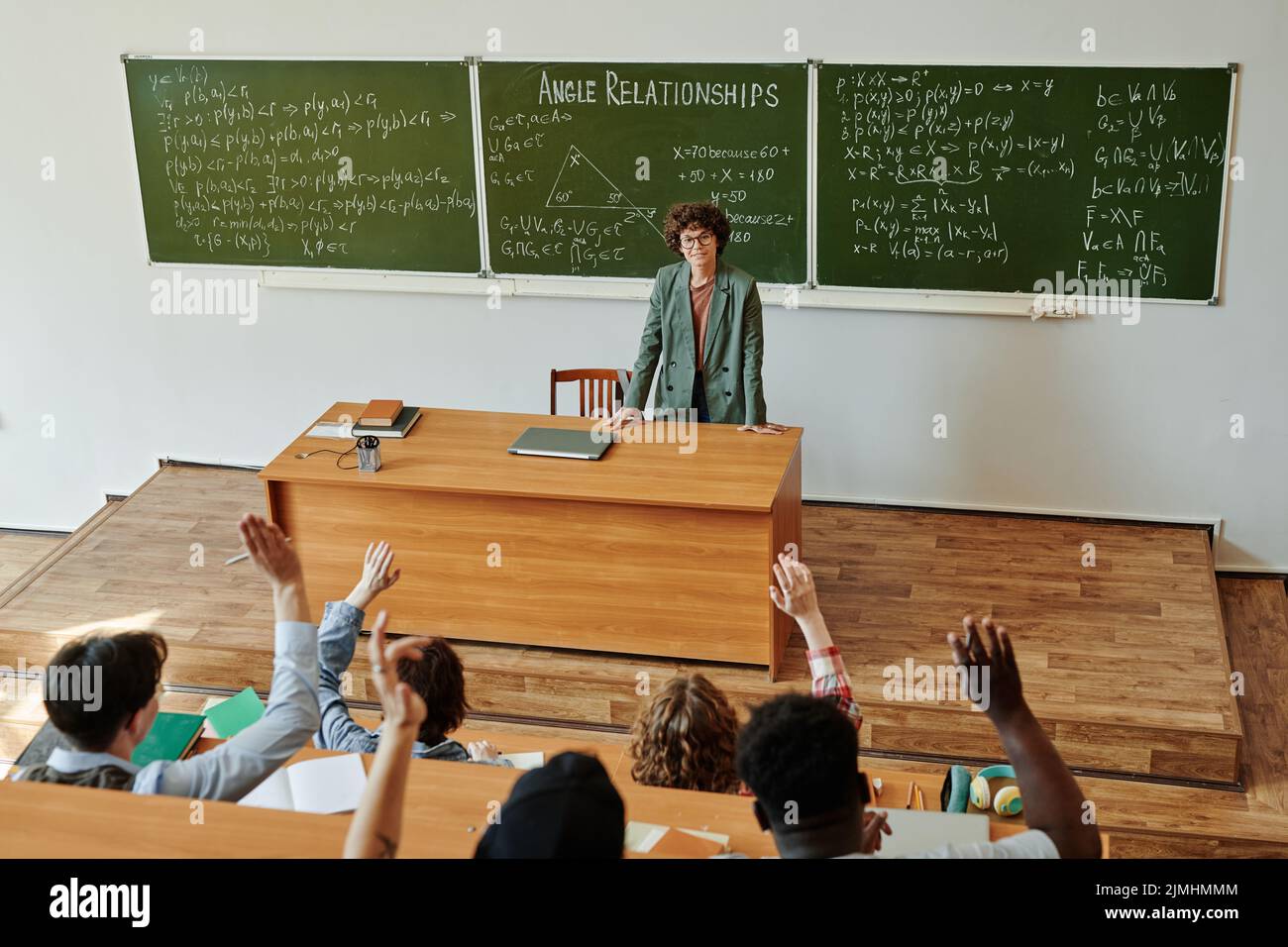 Group of interracial students raising hands to ask questions to teacher ...
