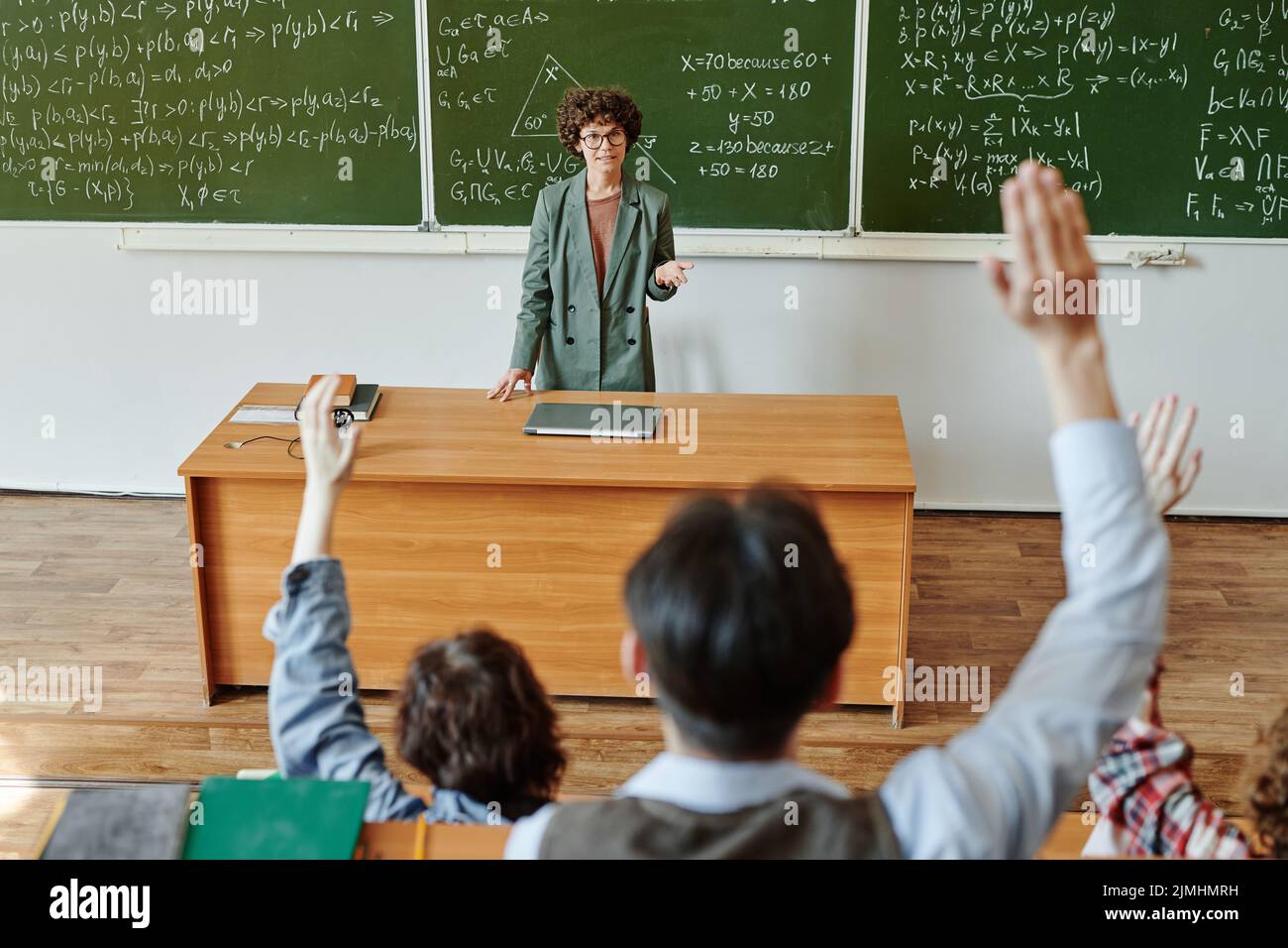 Confident teacher standing by blackboard with formulas and equations ...