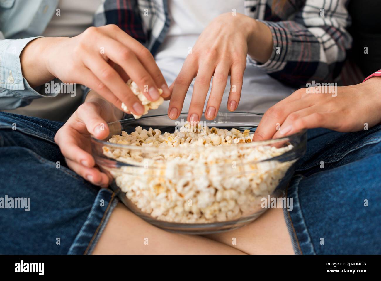 Bowl with popcorn hands girl sitting cross legged sofa Stock Photo - Alamy