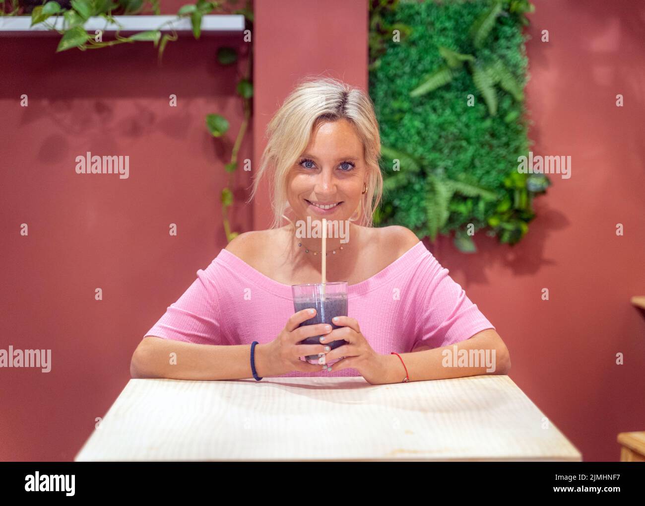 Young woman looking at the camera and smiling enjoying drinking a ...