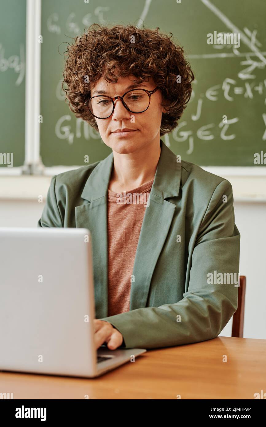 Young serious teacher concentrating on work with electronic documents ...