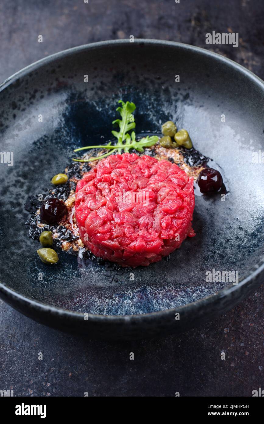 Modern style gourmet tartar raw from beef filet with capers and amarena ...