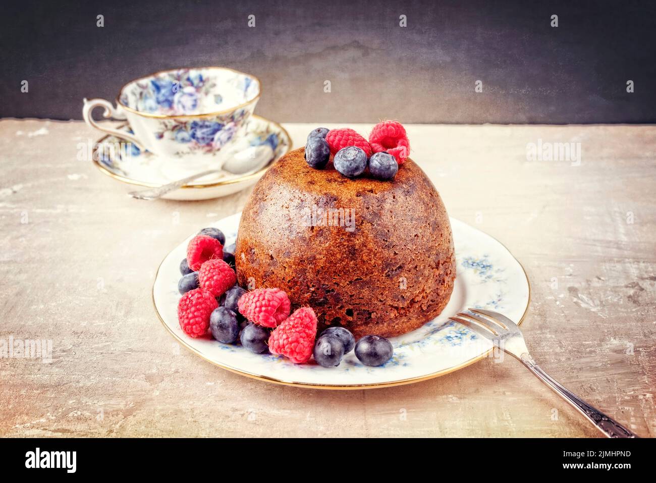 Traditional Australian plum pudding as closeup with fruits on a dessert ...