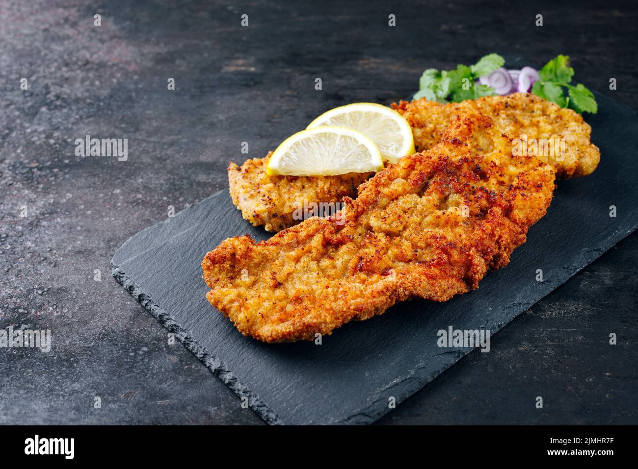 Traditional deep-fried schnitzel with lemon slices and onion rings ...