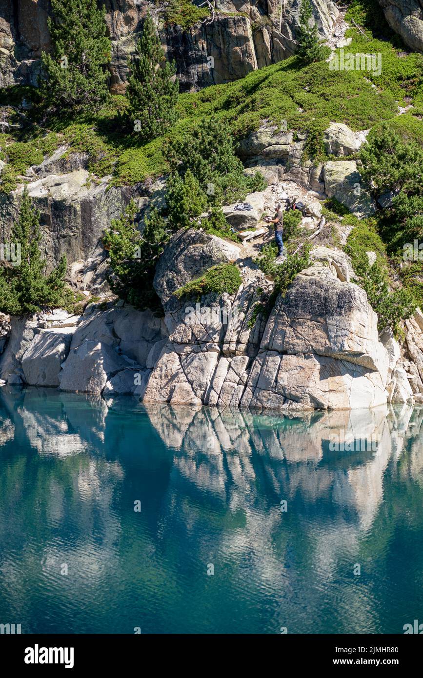 trout fisherman stands high on rocks at the Barrage dam and Lac de Cap ...