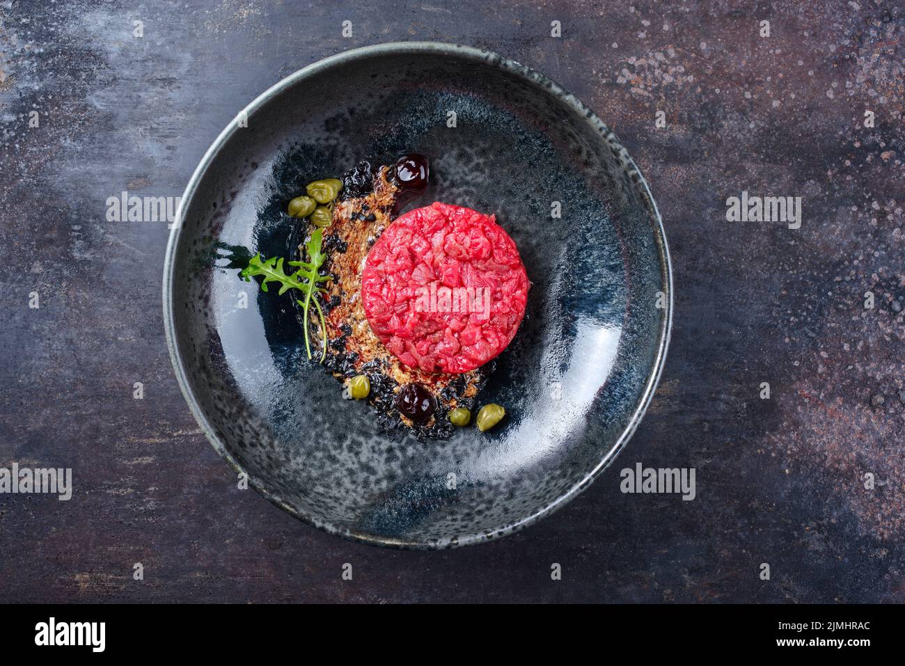 Modern style gourmet tartar raw from beef filet with capers and amarena ...