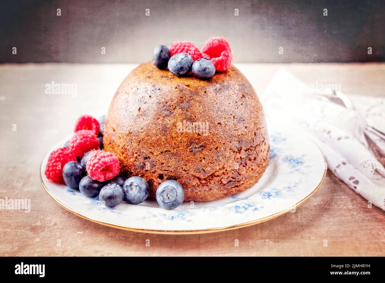 Traditional Australian plum pudding as closeup with fruits on a dessert ...