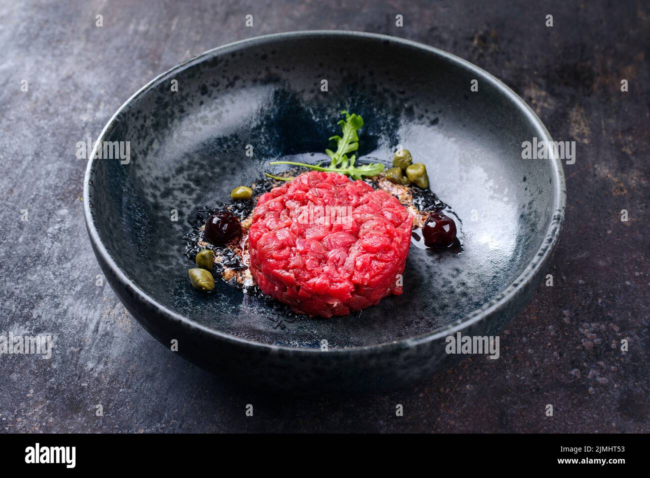 Modern style gourmet tartar raw from beef filet with capers and amarena ...