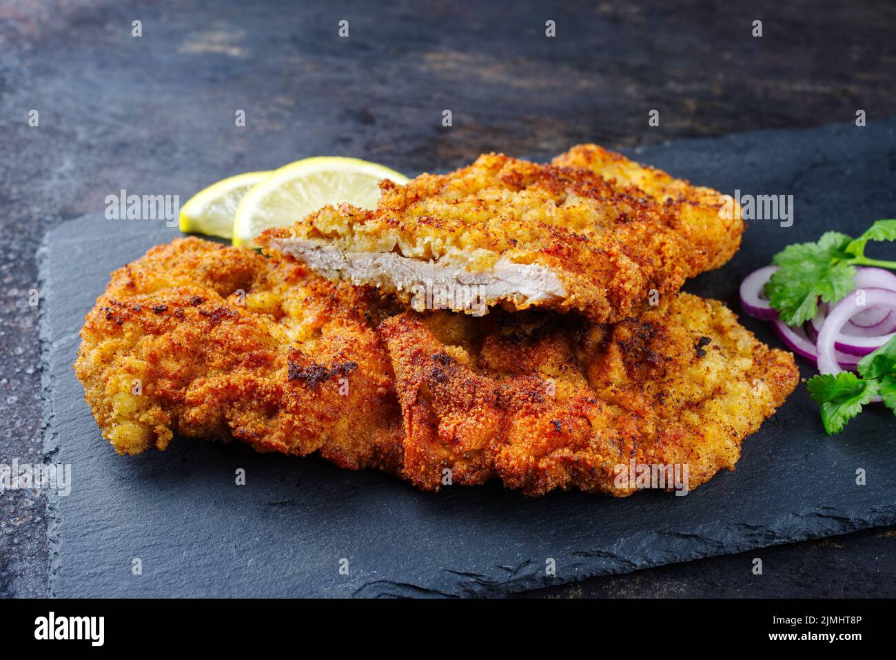 Traditional deep-fried schnitzel with lemon slices and onion rings ...