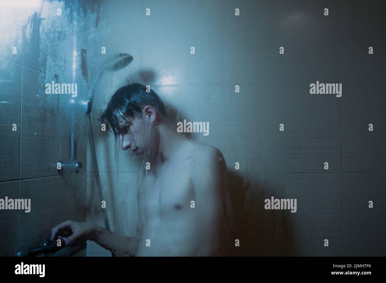 A male taking a shower with a depressed mood Stock Photo - Alamy