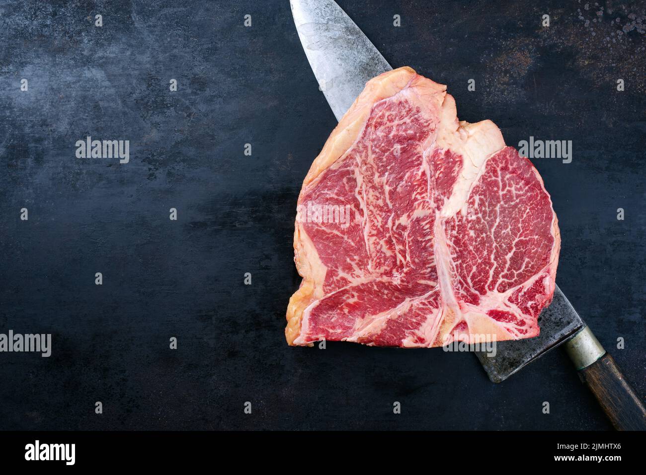 Raw dry aged wagyu porterhouse beef steak on a large knife offered as ...