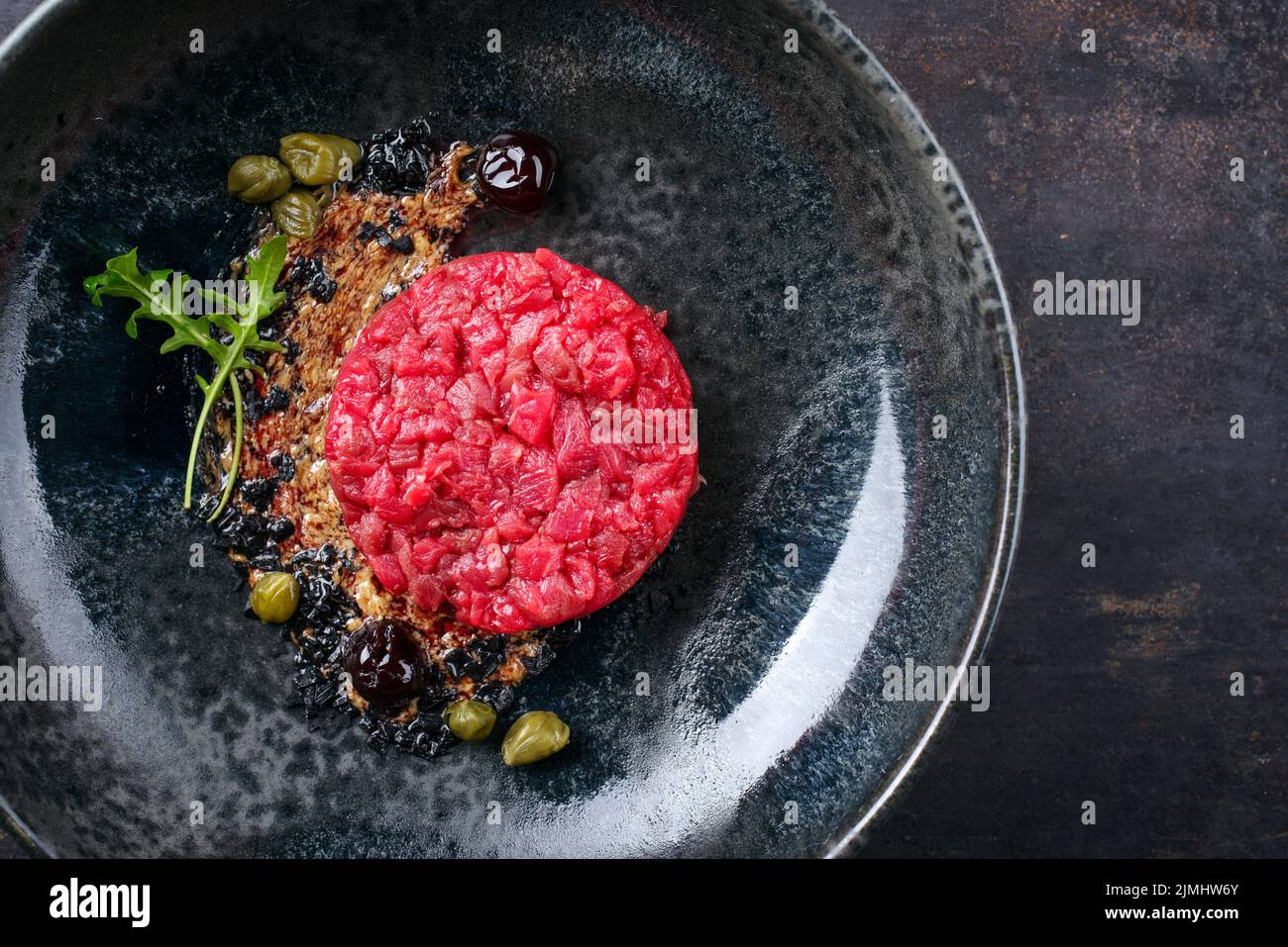 Modern style gourmet tartar raw from beef filet with capers and amarena ...
