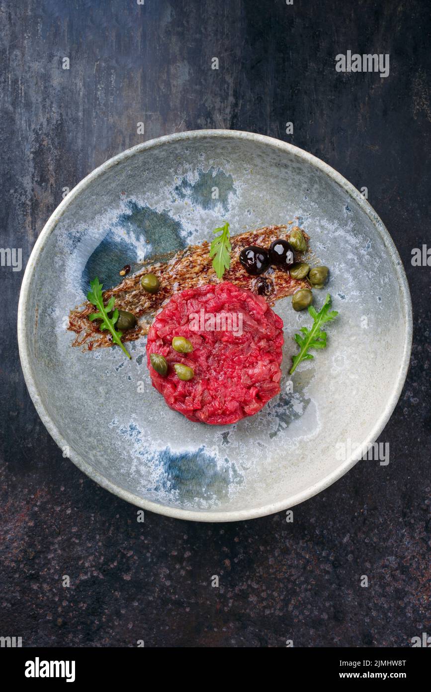 Modern style gourmet tartar raw from beef filet with capers and amarena ...