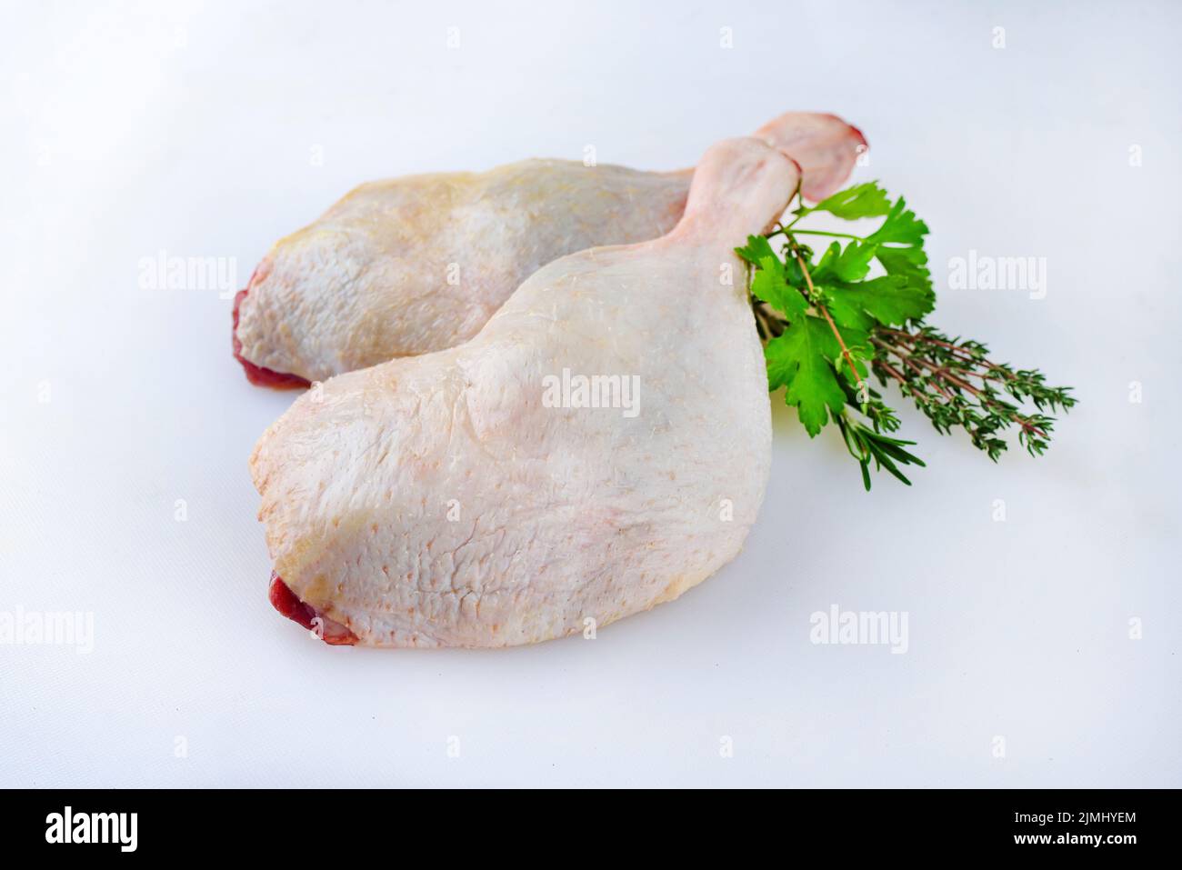 Traditional raw gourmet duck leg offered with herbs as close-up on a ...