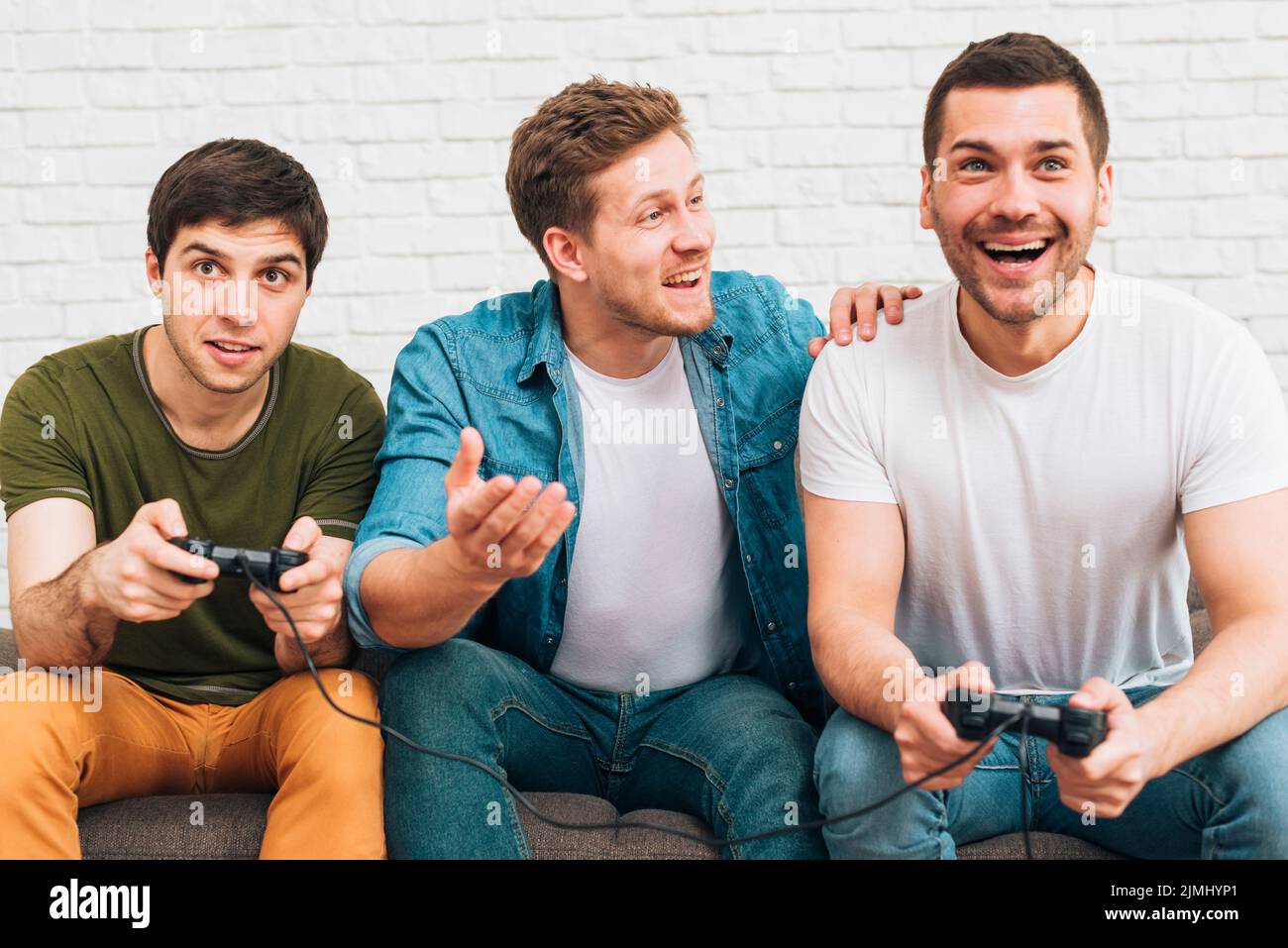 Three male friends sitting together enjoying video game Stock Photo - Alamy Three male friends sitting together enjoying video game Stock Photo - Alamy