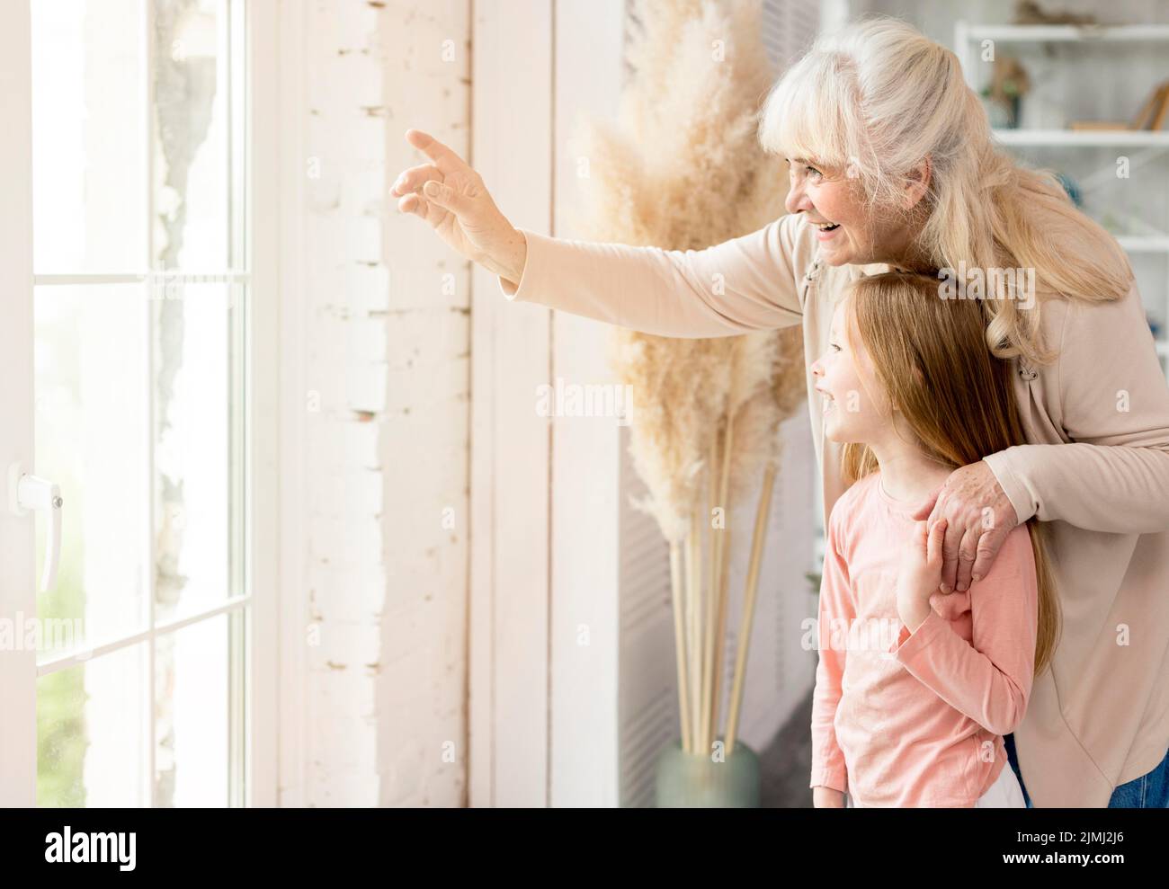 Grandma with girl home looking window Stock Photo - Alamy