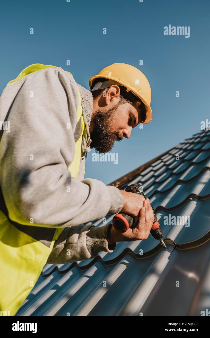Man working roof with drill low view Stock Photo - Alamy