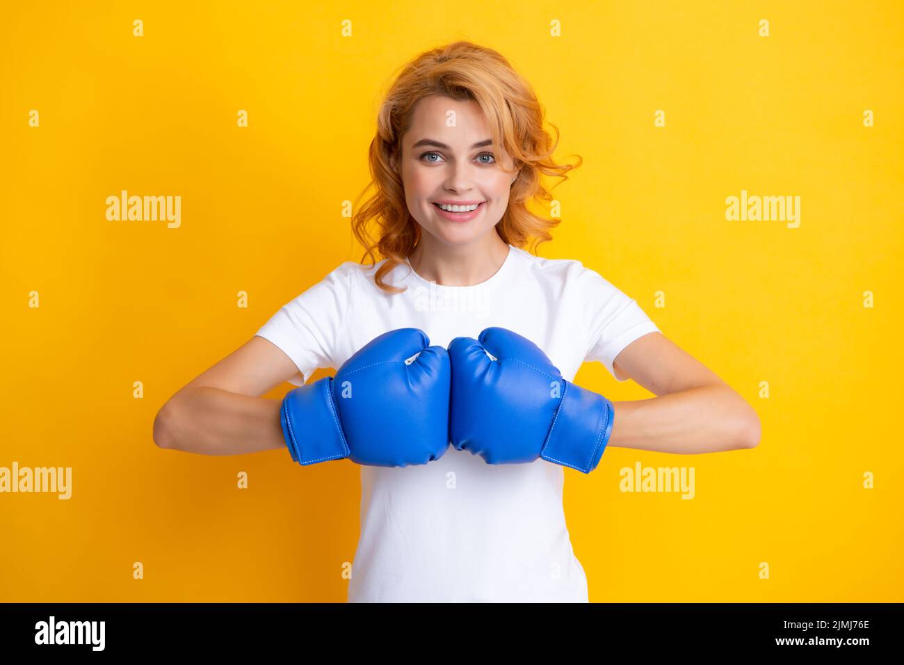 Woman in boxing gloves in yellow isolated background. Successful young ...