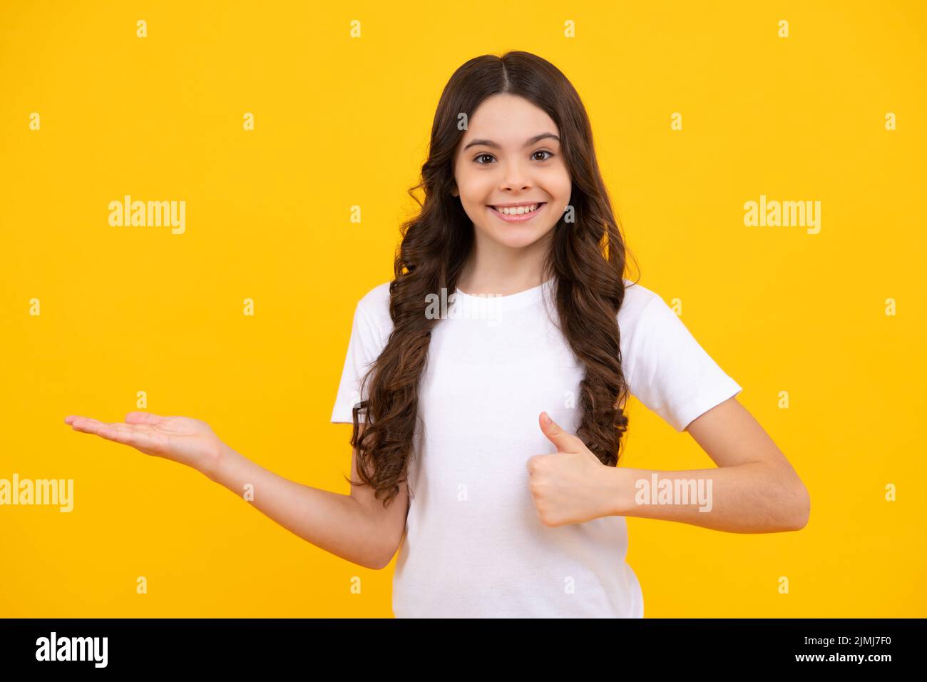 Positive teenager child points aside with cheerful expression, shows ...